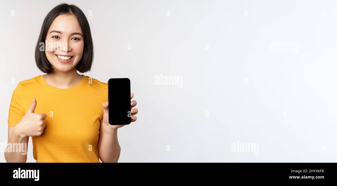 Technology and people concept. Smiling young woman showing thumb up and ...