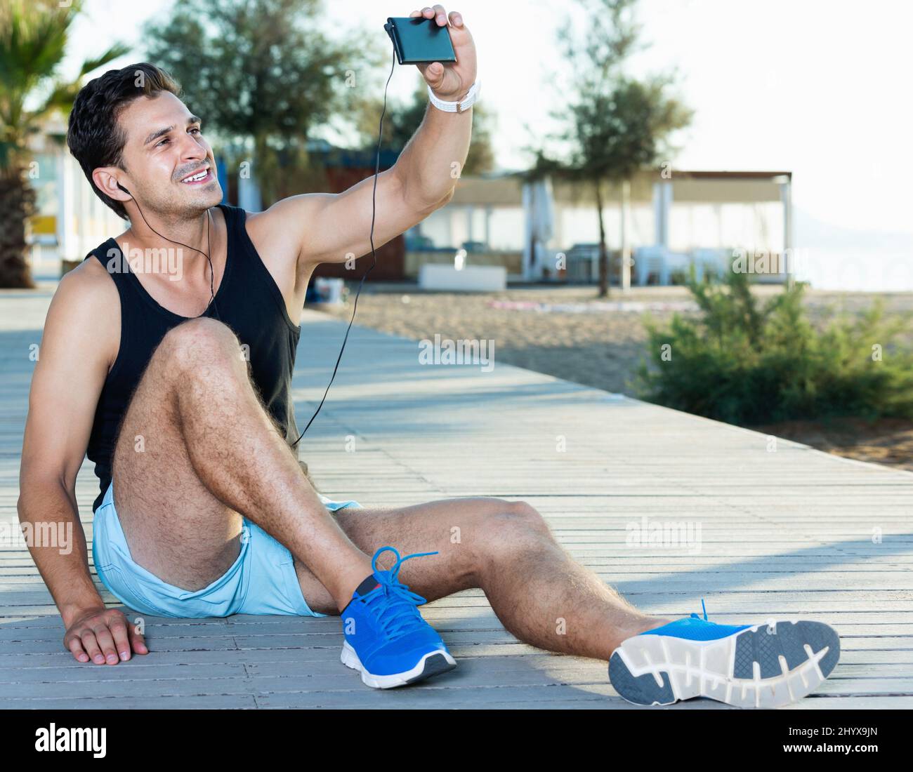 Smiling athletic man making selfie during break in workout outdoors ...