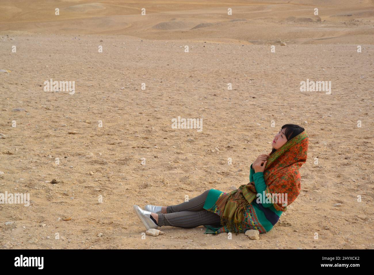 High angle view of a Chinese female sitting on the sand in the Sahara ...