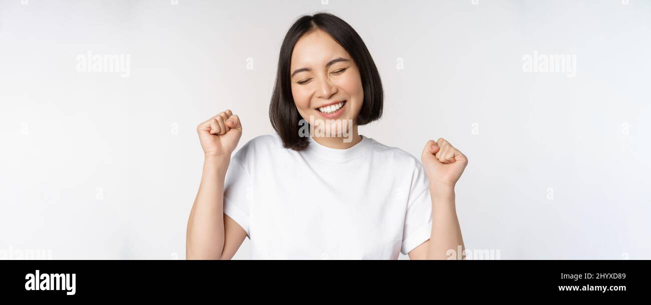 Dancing asian girl celebrating, feeling happy and upbeat, smiling ...
