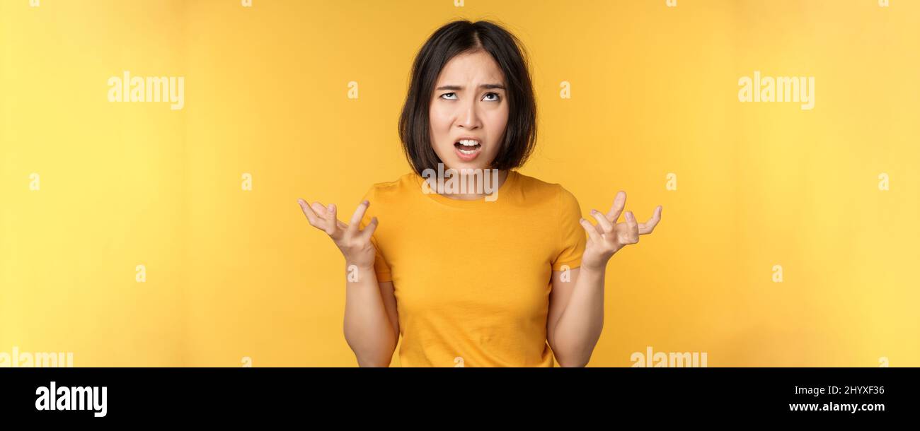 Image of angry asian woman, shouting and cursing, looking outraged ...