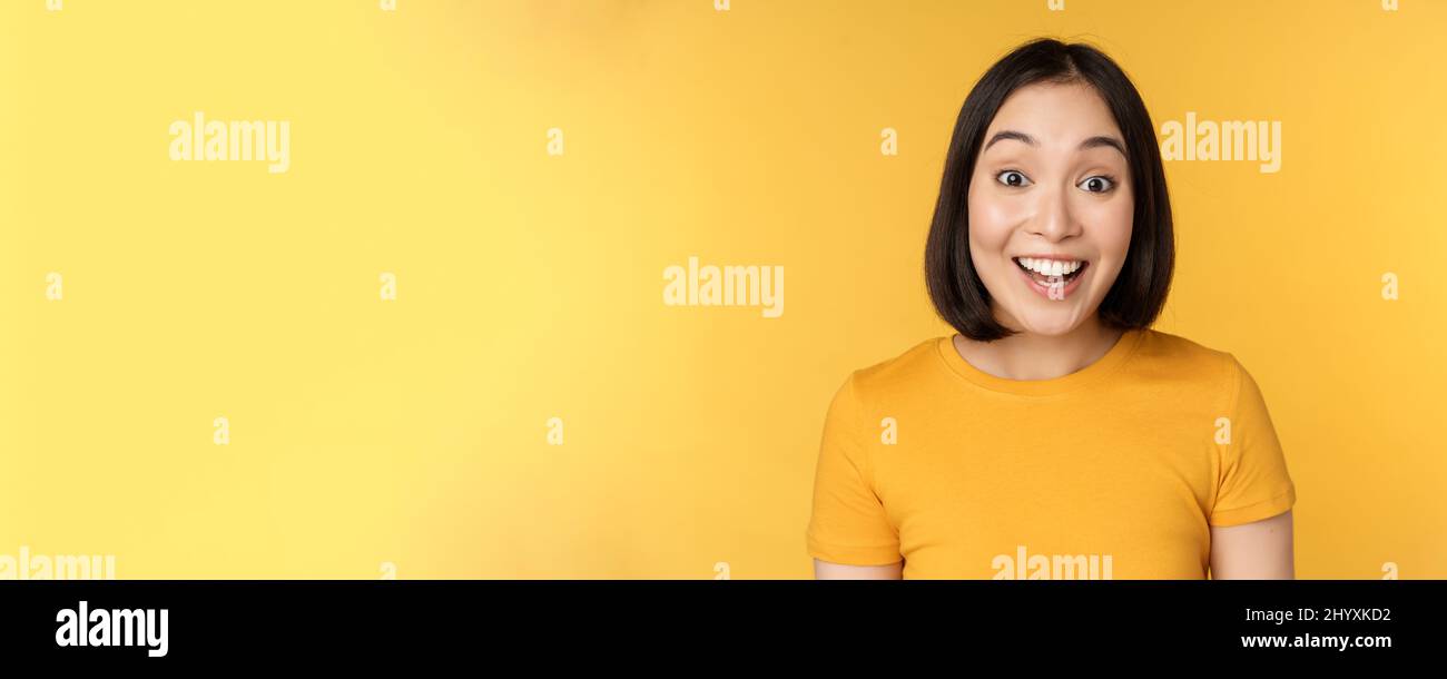 Close up portrait of asian girl showing surprised reaction, raising ...