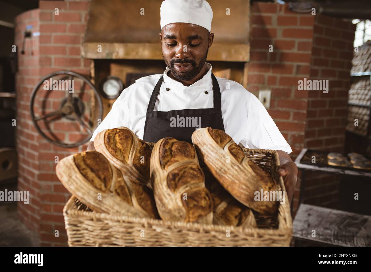 African american mid adult male baker holding breads in wicker basket ...