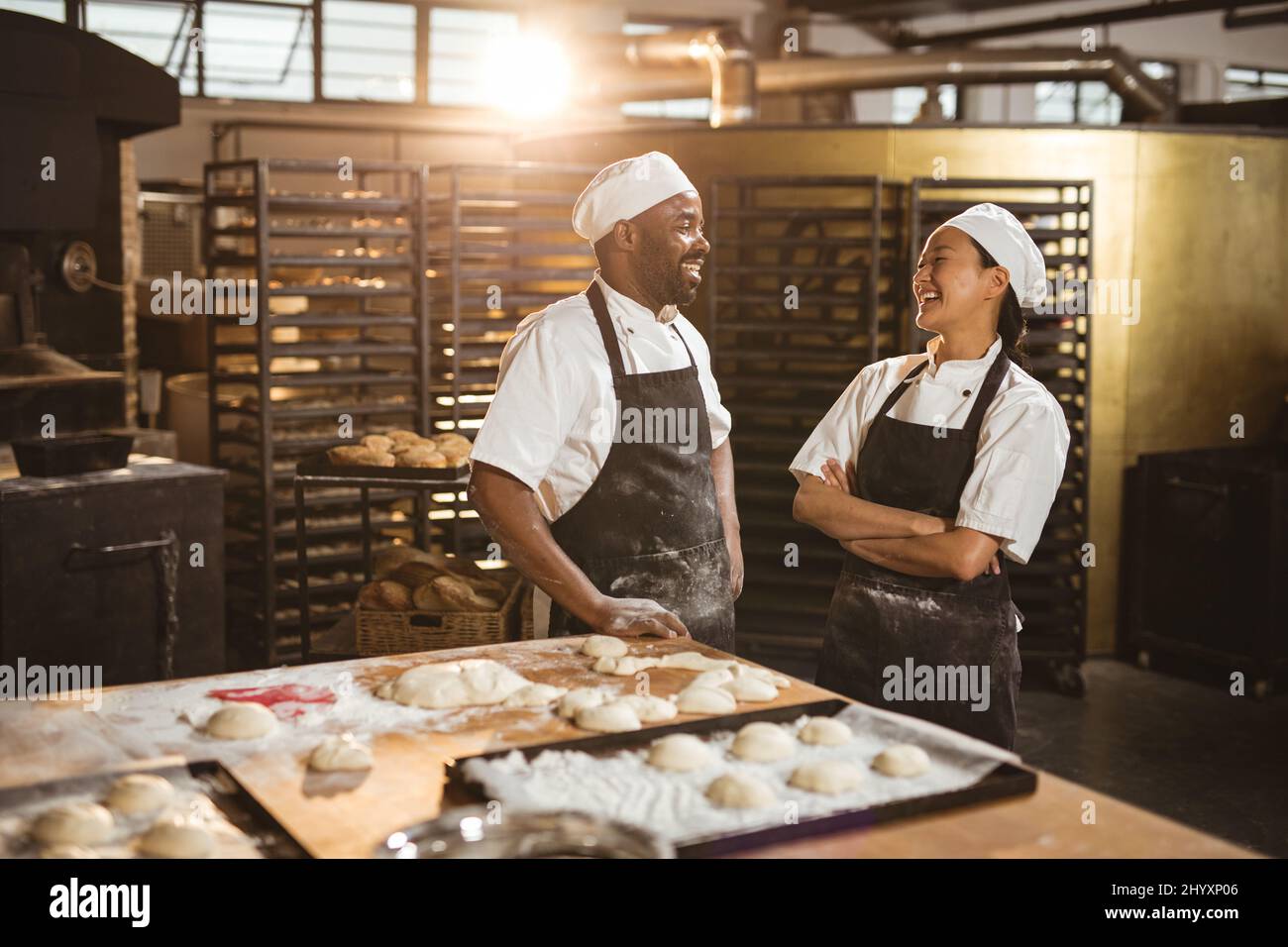 Smiling mid adult multiracial male and female bakers talking while ...