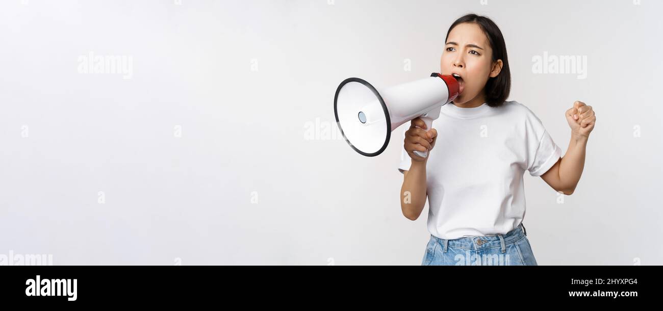 Asian girl shouting at megaphone, young activist protesting, using loud ...