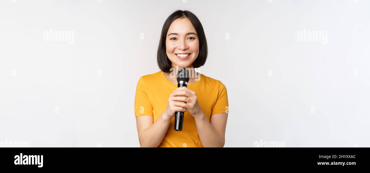 Image of young asian woman talking in microphone, perfom with mic ...
