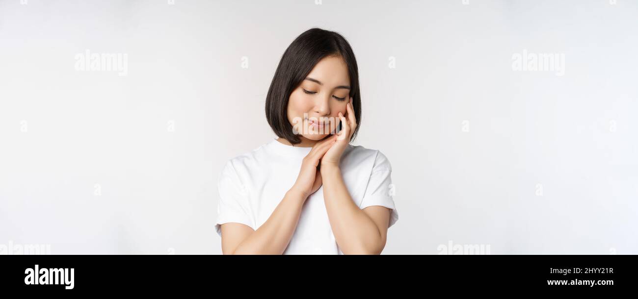 Portrait of tender and feminine young asian woman, looking down, gently ...