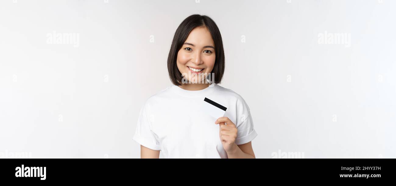 Portrait of korean smiling girl, bank client, showing credit card with ...