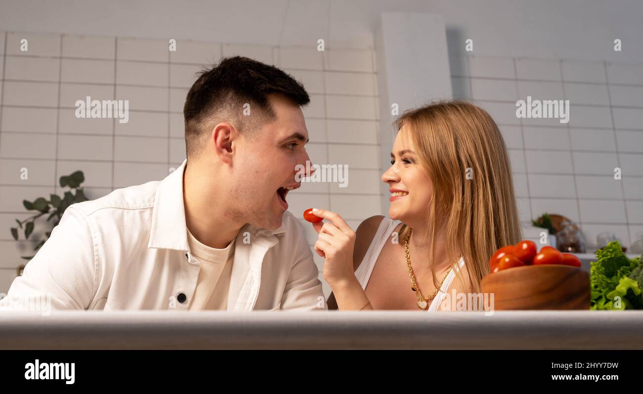 Happy couple cooking at home. Beautiful woman feeding handsome man ...