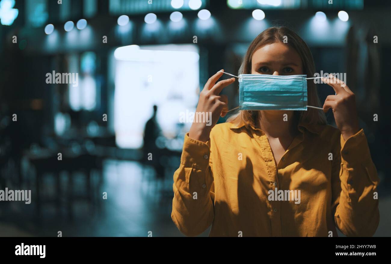 Woman putting on a medical mask on the street. Wear mask in public ...
