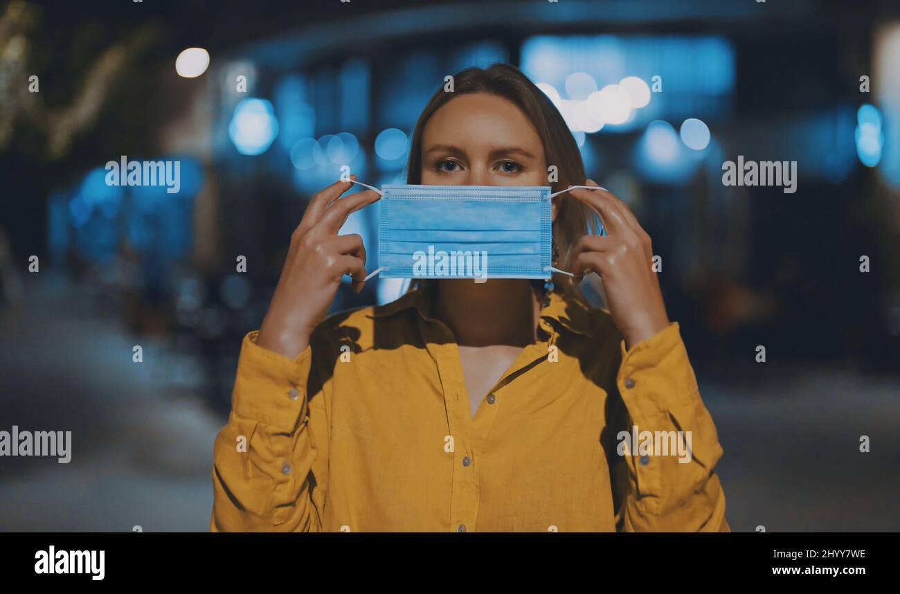 Woman putting on a medical mask on the street. Wear mask in public ...