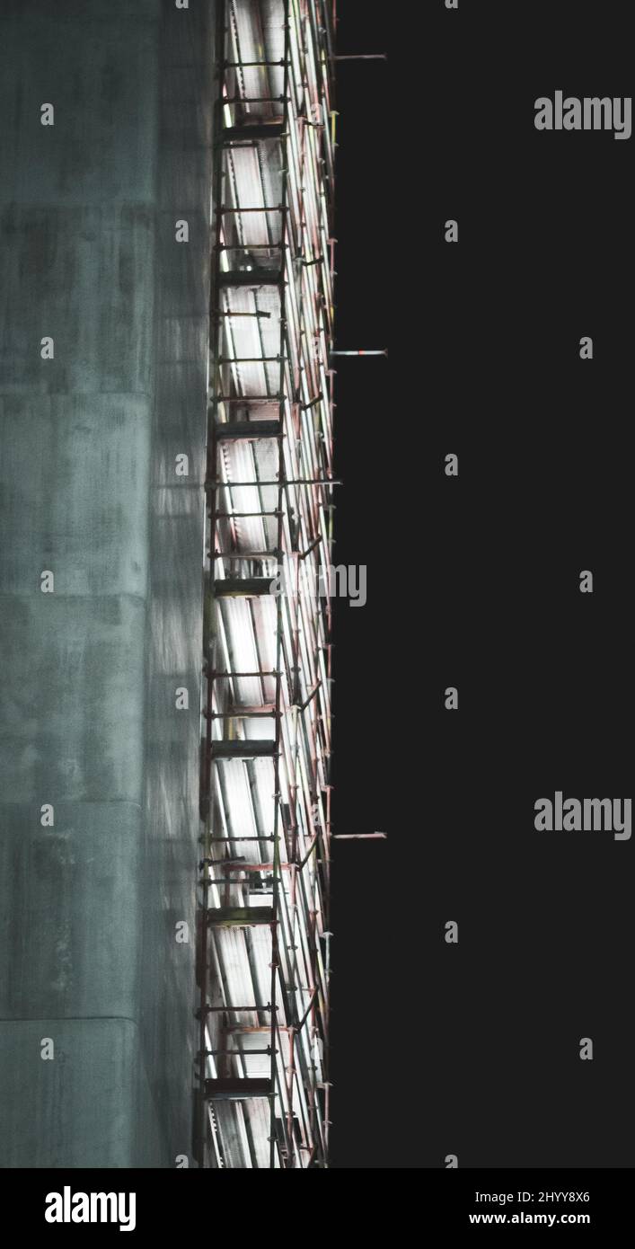 Fire escape stairs on the high-rise building wall. Night street ...