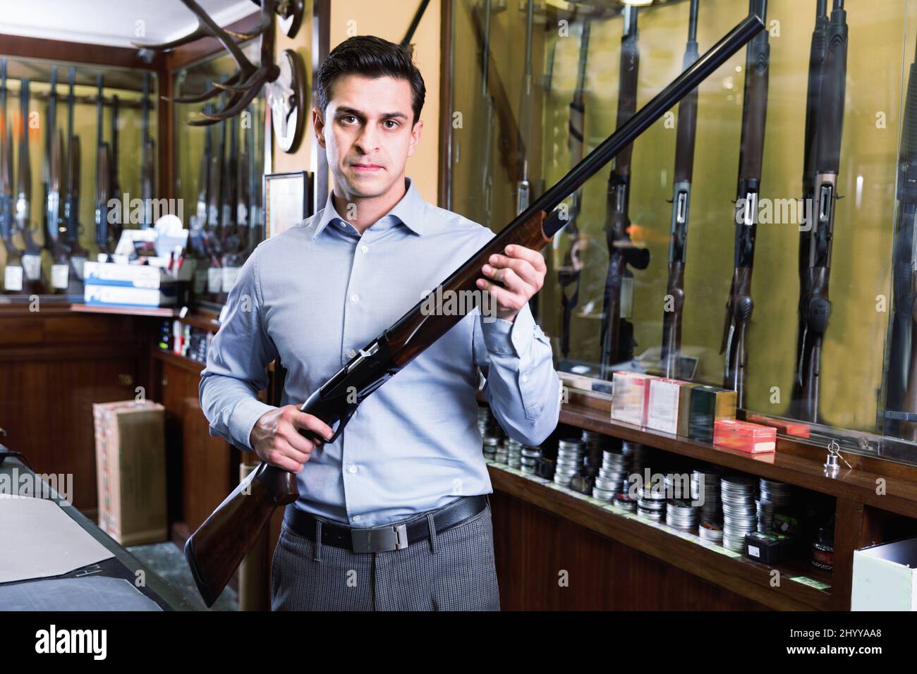 Handsome adult male in hunting shop with rifle in hands Stock Photo - Alamy