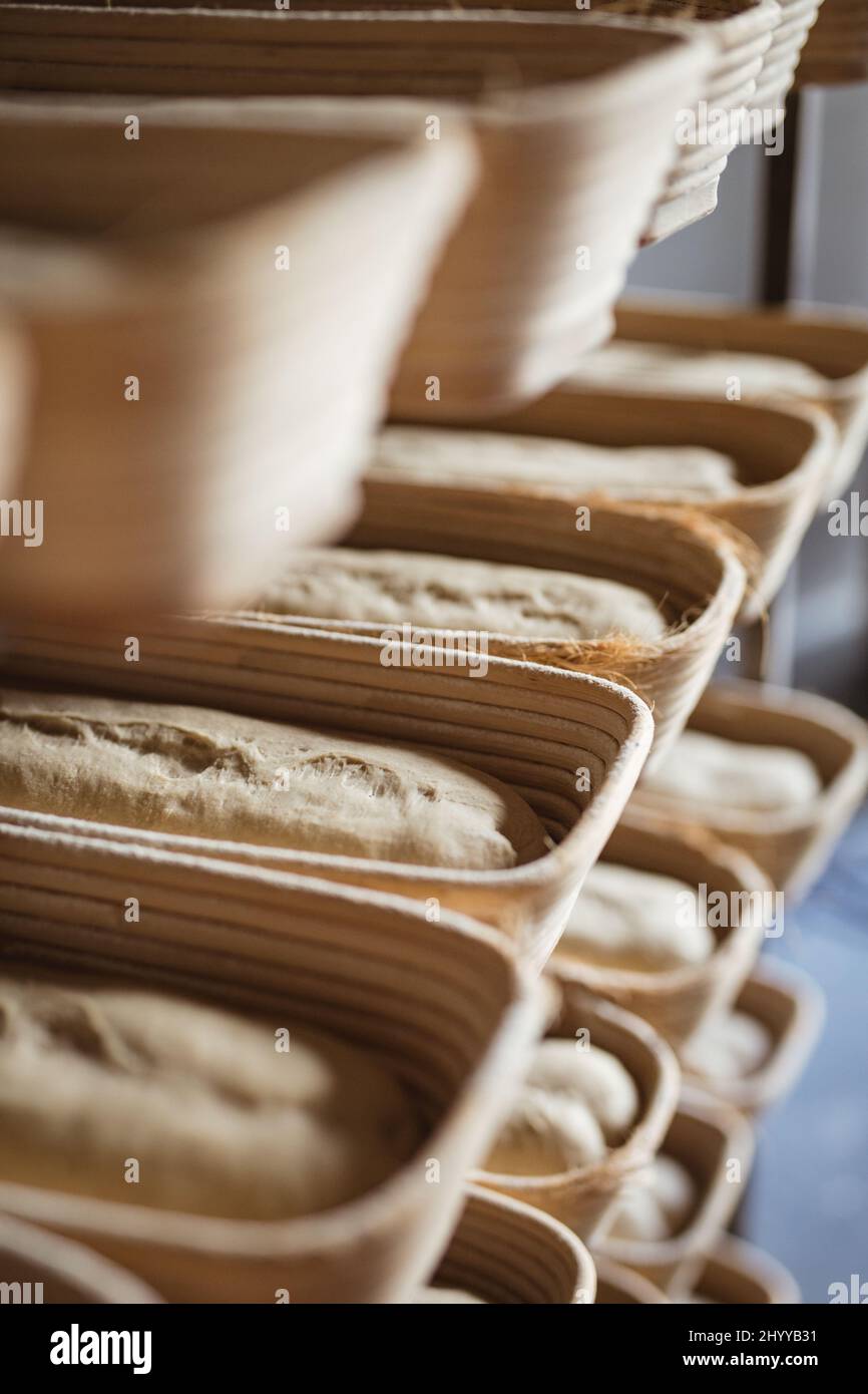 Close-up of dough in wicker containers arranged on rack in bakery Stock ...