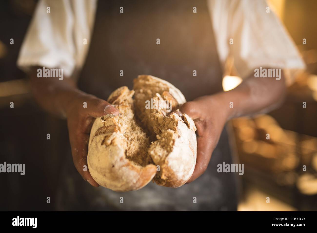 Mid section of african american mid adult male baker breaking bread ...