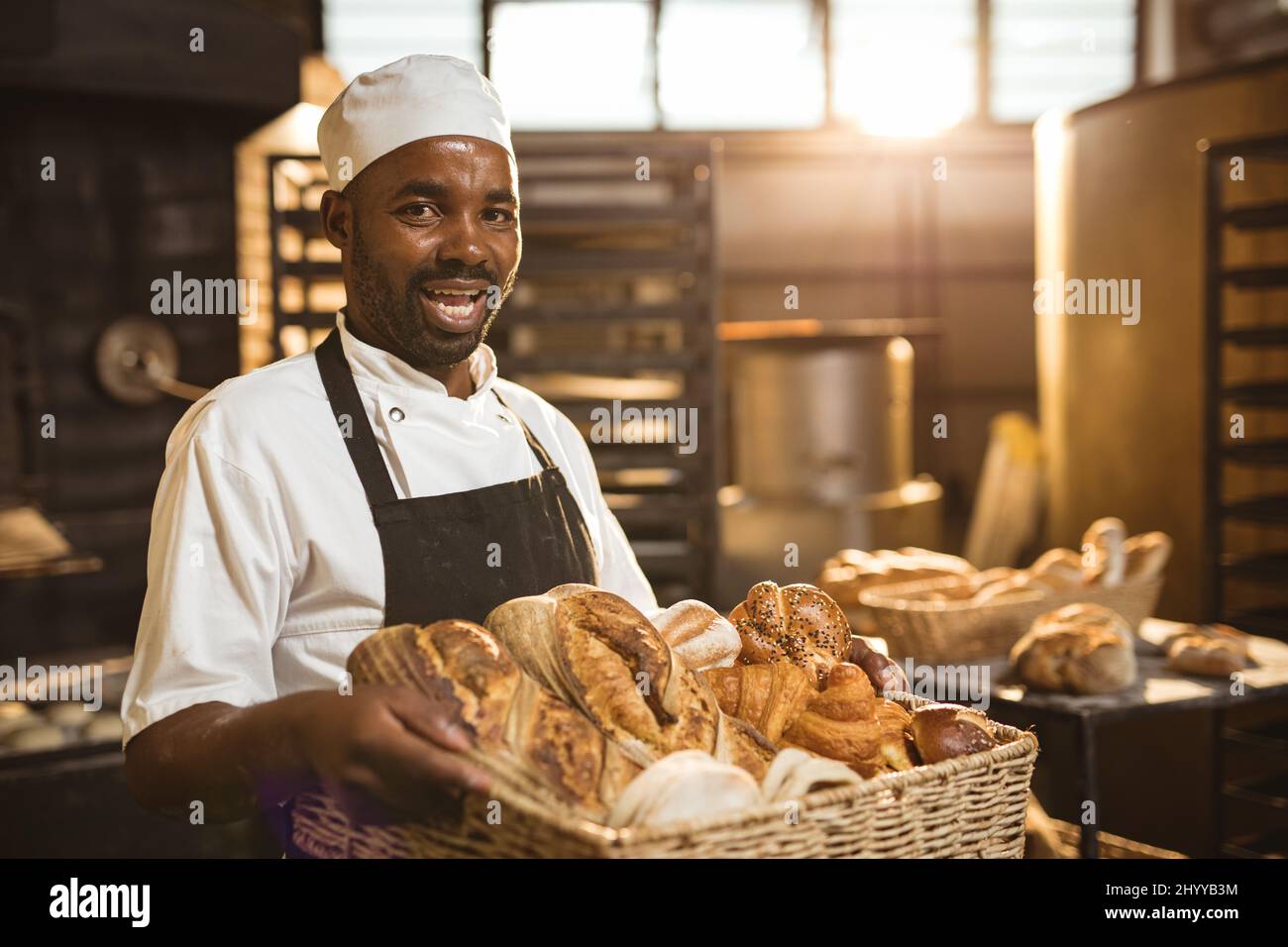 Portrait of african american mid adult male baker holding basket with ...