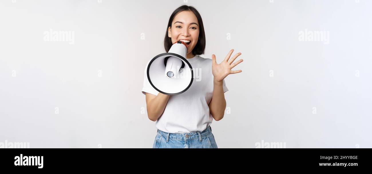 Happy asian woman shouting at megaphone, making announcement ...