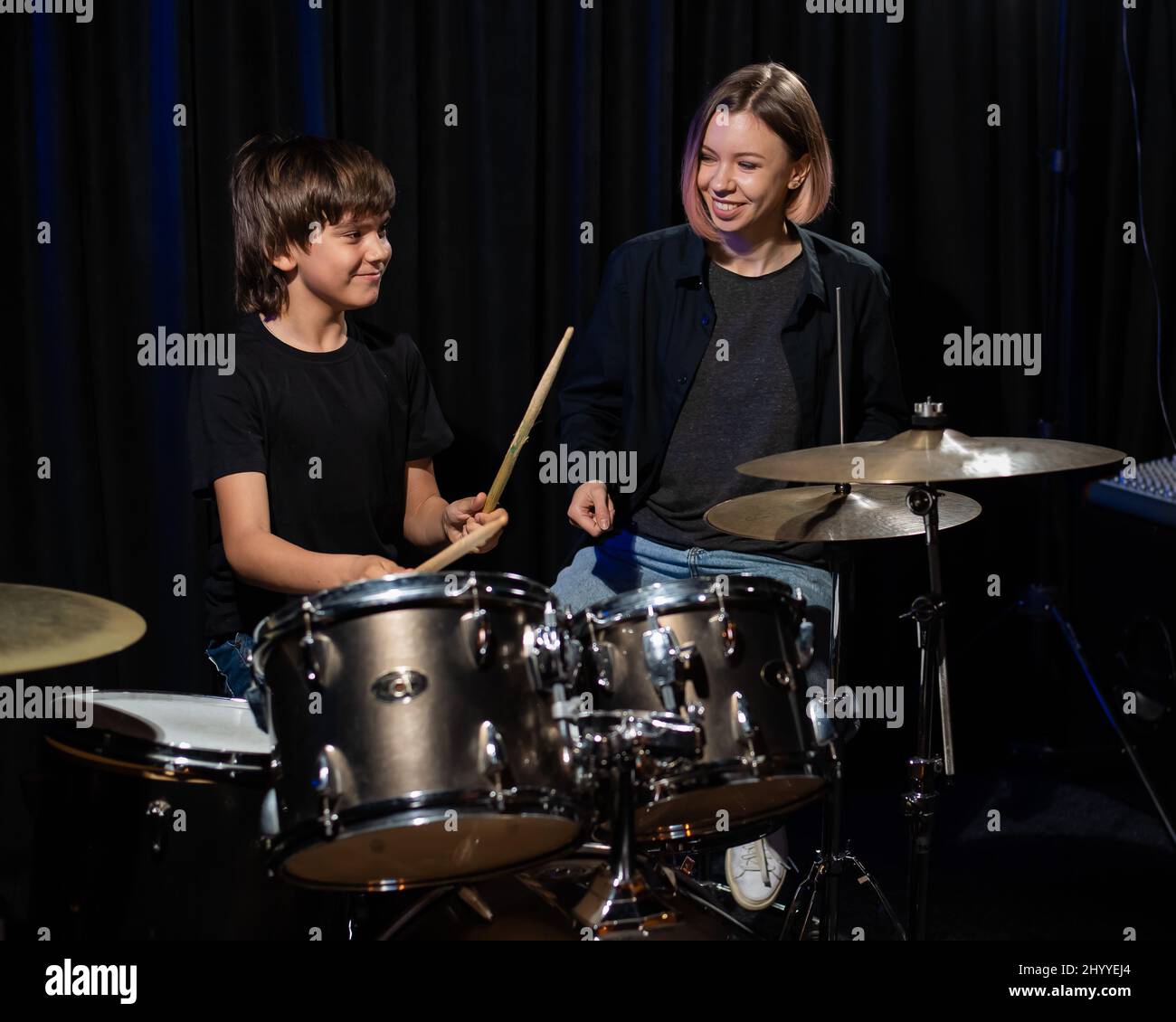 Young woman teaching boy to play drums Stock Photo - Alamy