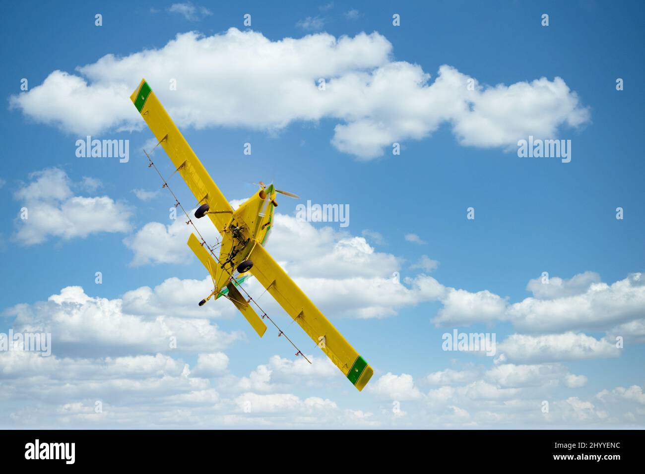 The underside of a yellow crop dusting sptay plane flying in the air ...
