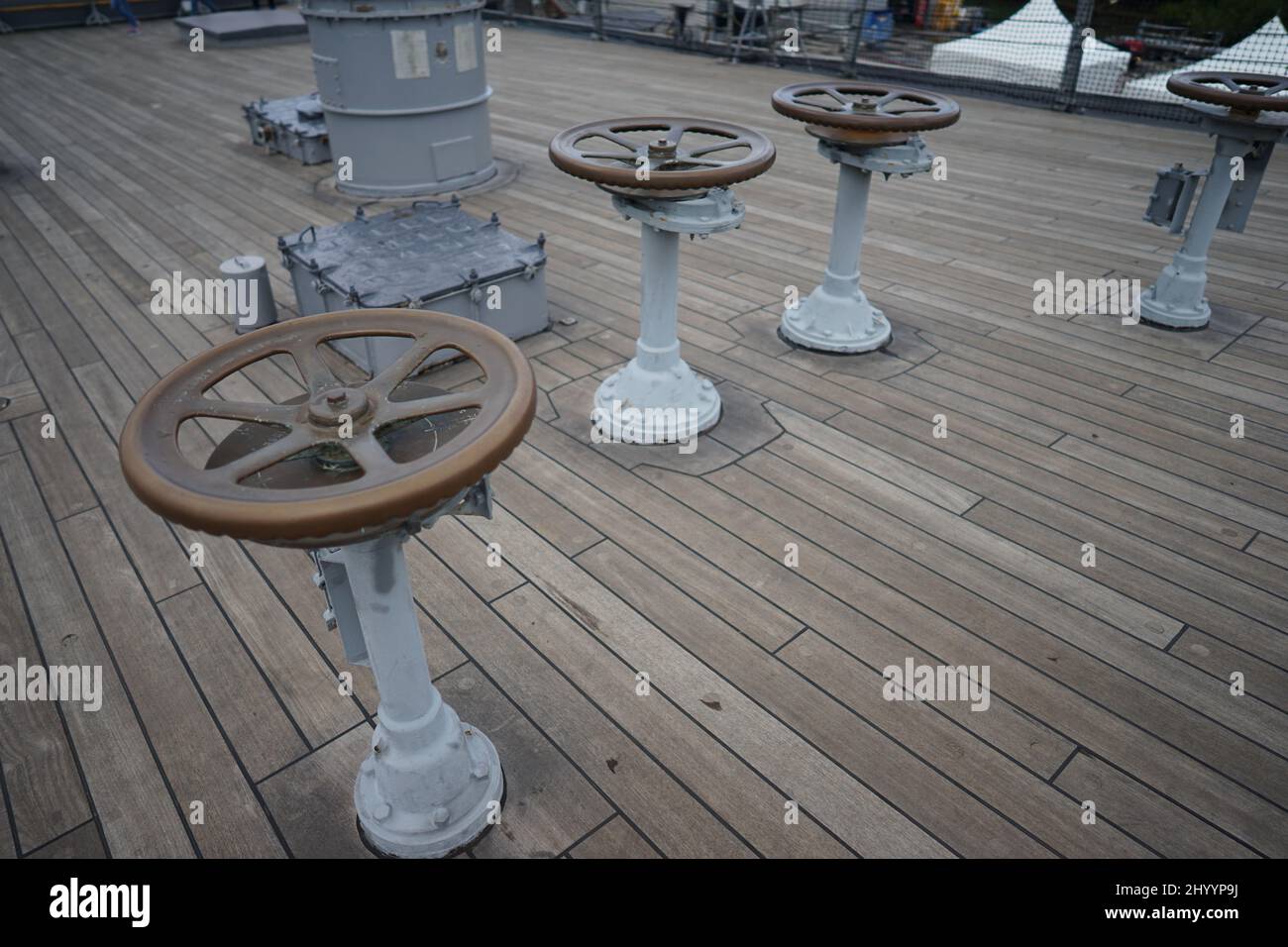 Teak wood ship deck of a battleship with brass valves Stock Photo - Alamy