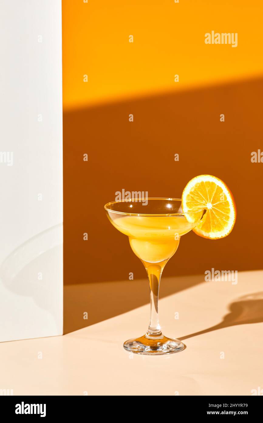 Graphic still life of single cocktail glass with fresh orange juice ...