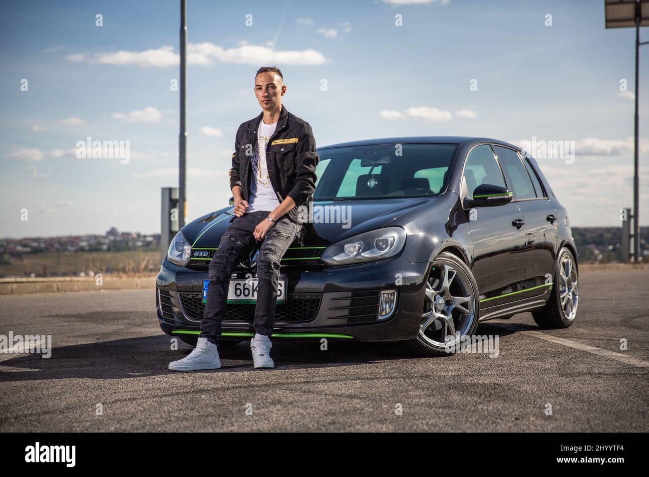 Young male posing in front of a car Stock Photo - Alamy