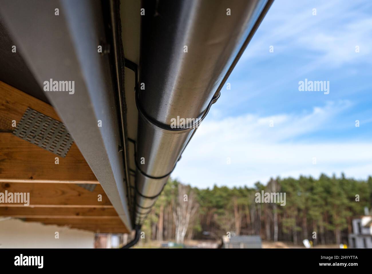 A metal, black gutter on a roof covered with ceramic tiles in the ...