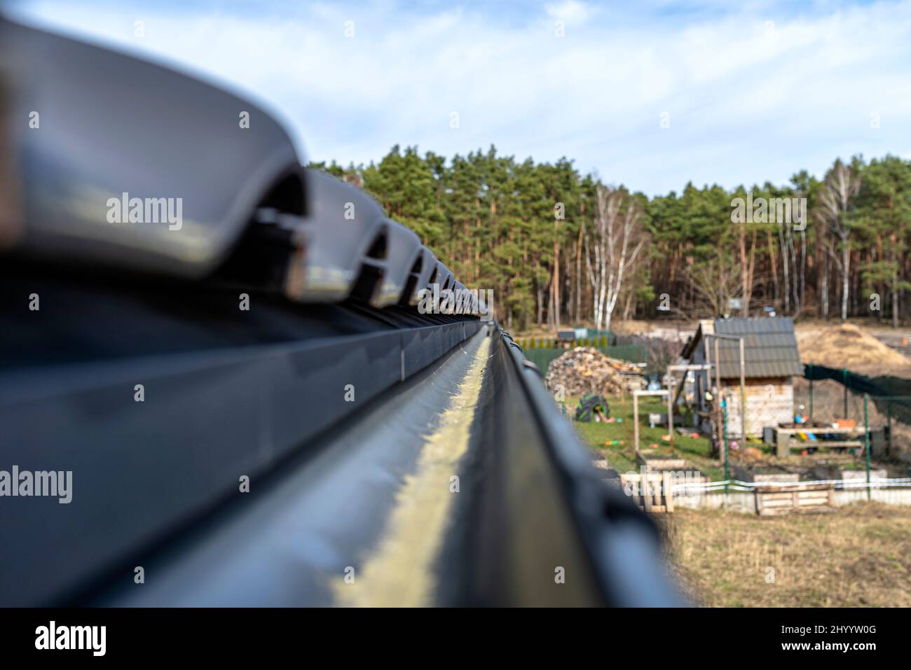 A metal, black gutter on a roof covered with ceramic tiles in the ...