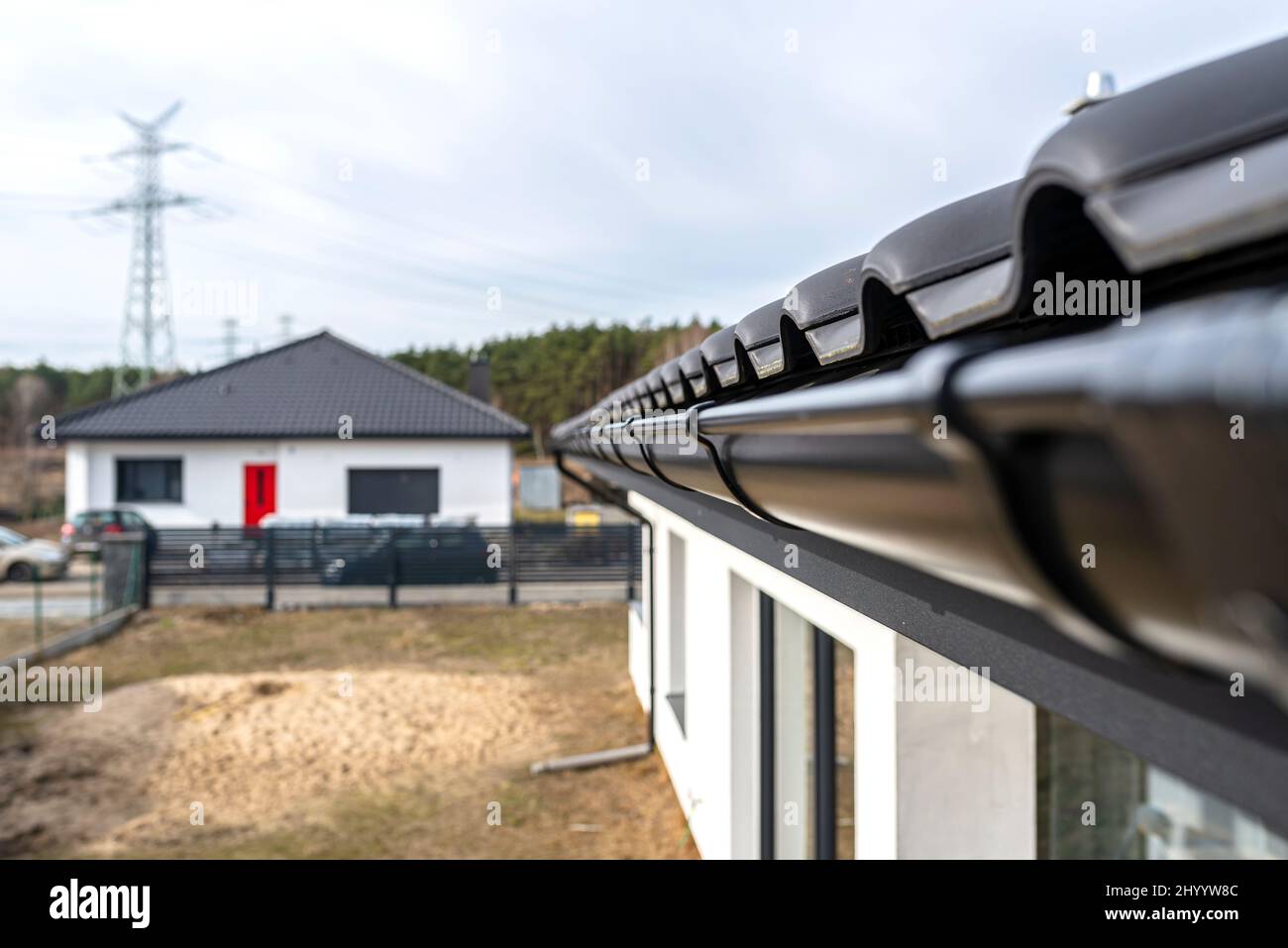 A metal, black gutter on a roof covered with ceramic tiles, visible ...