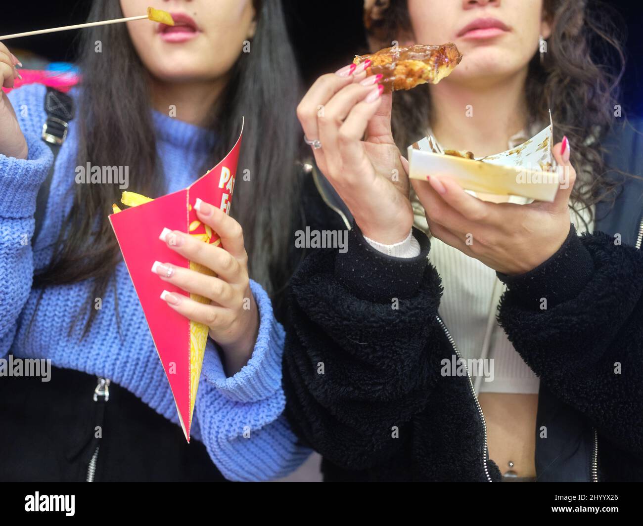 Close up view of two women eating fast food outdoors Stock Photo - Alamy