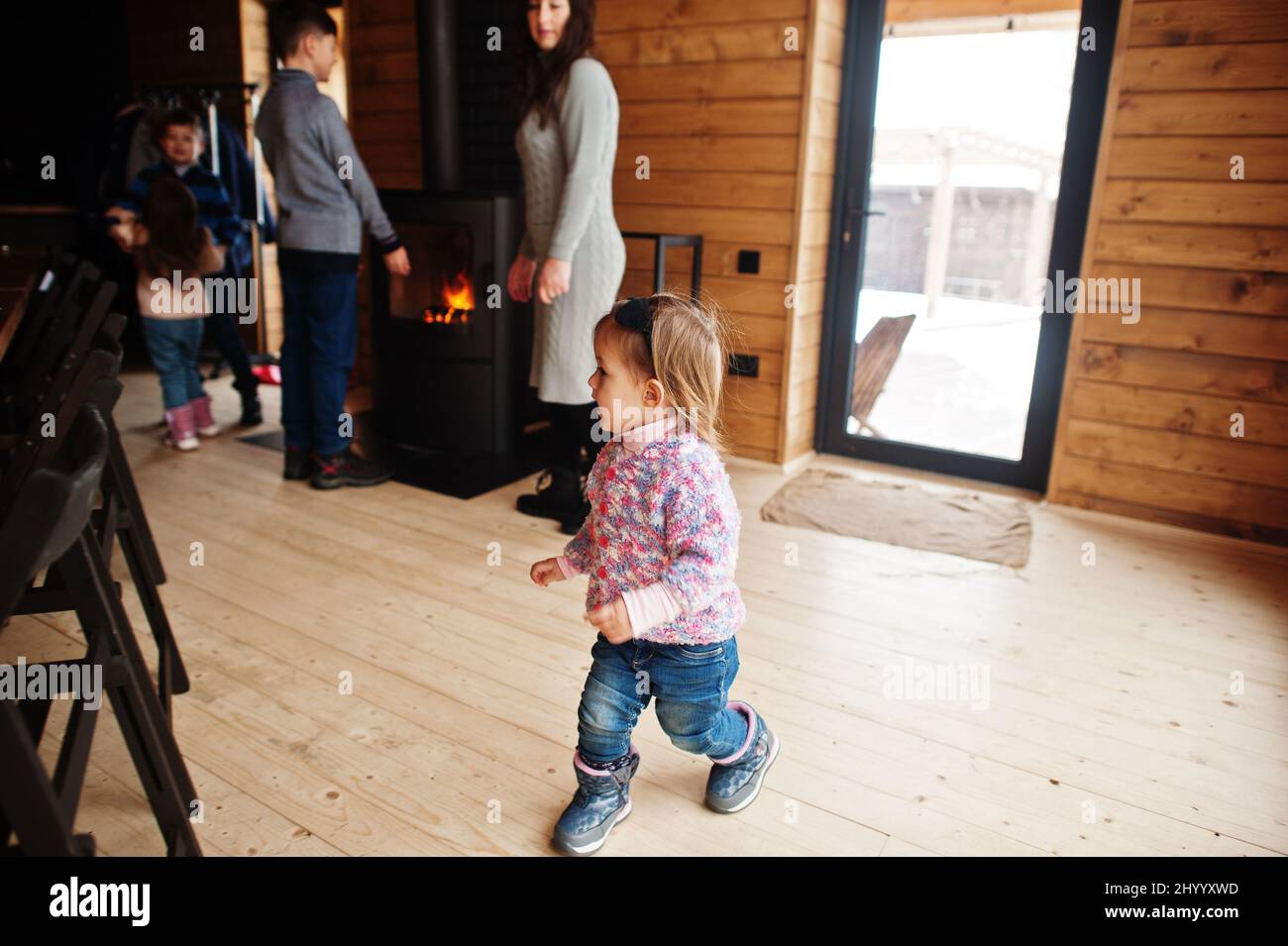 Mother and four kids in modern wooden house against fireplace, spending ...