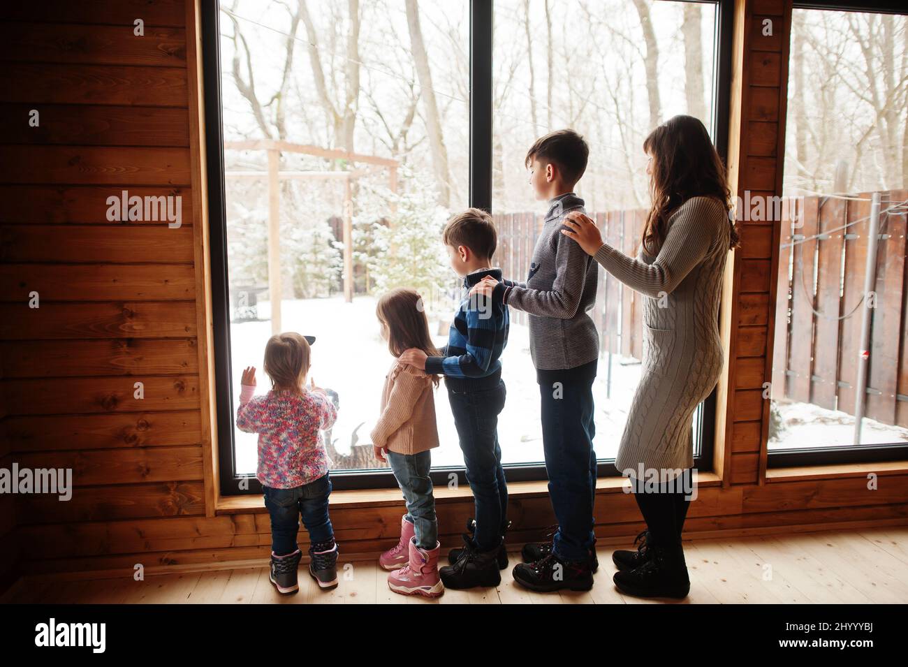 Mother and four kids in modern wooden house against large window Stock ...