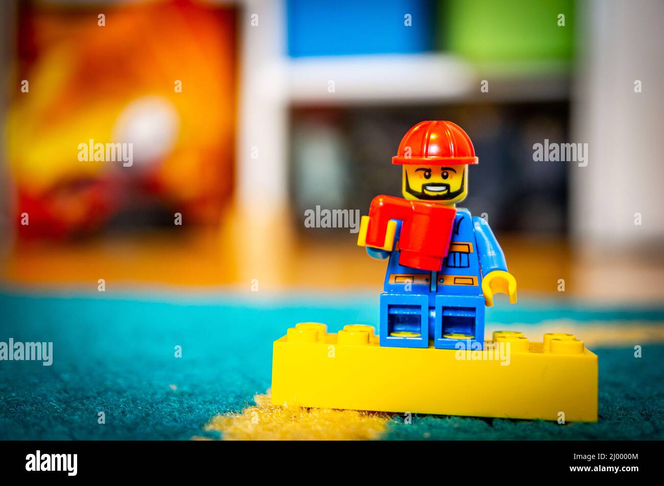 Lego brand toy figurine construction worker sitting and holding a cup ...