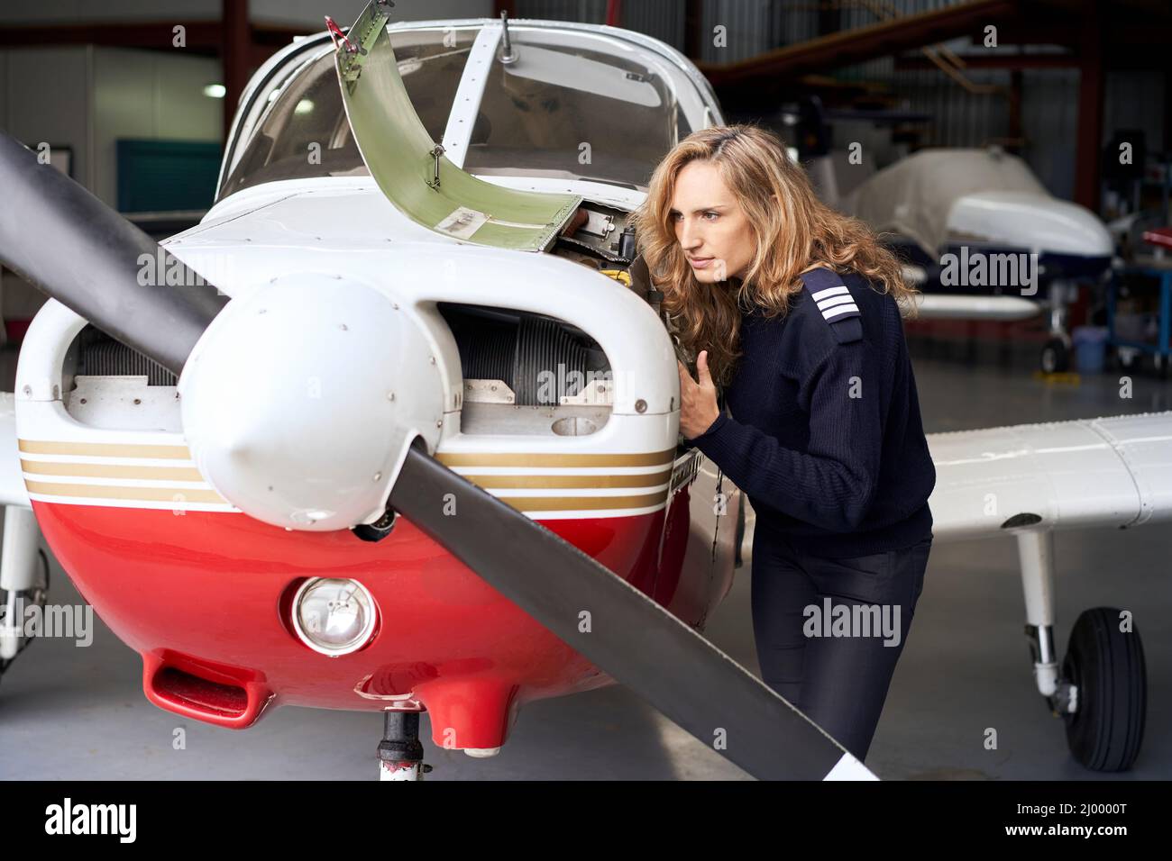 Pilot woman in the hangar doing the maintenance of the engine of a ...