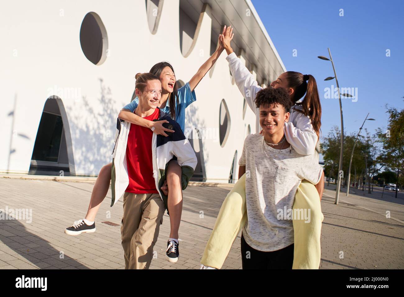 Multiracial young people stacking hands. Friends piggyback having fun ...