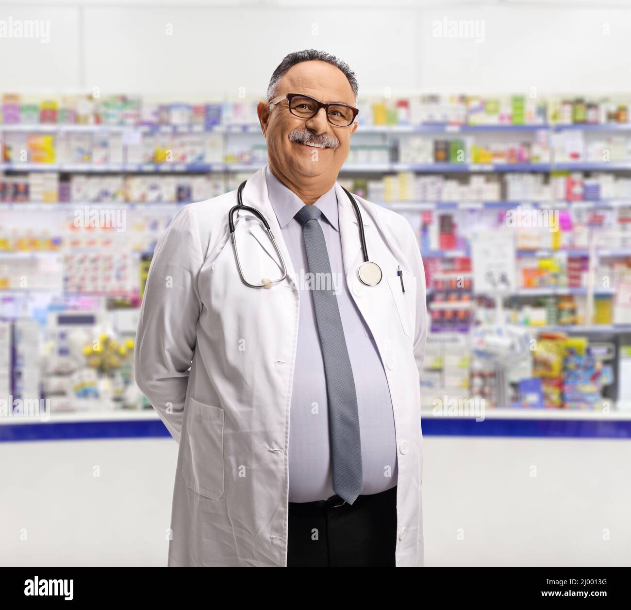 Mature male pharmacist in front of a pharmacy counter smiling at camera ...