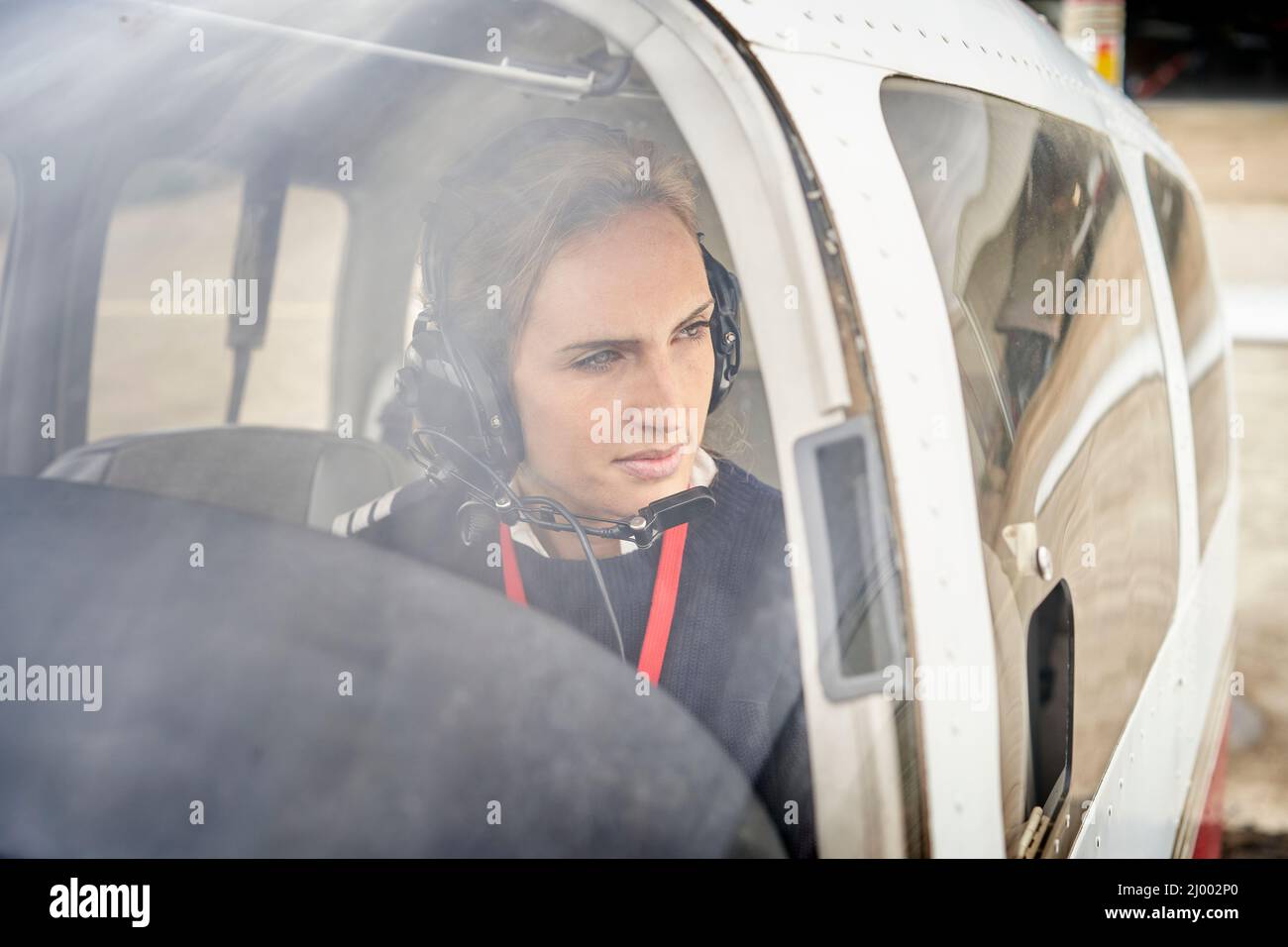 Front view from outside of a female pilot in the cockpit of an airplane ...