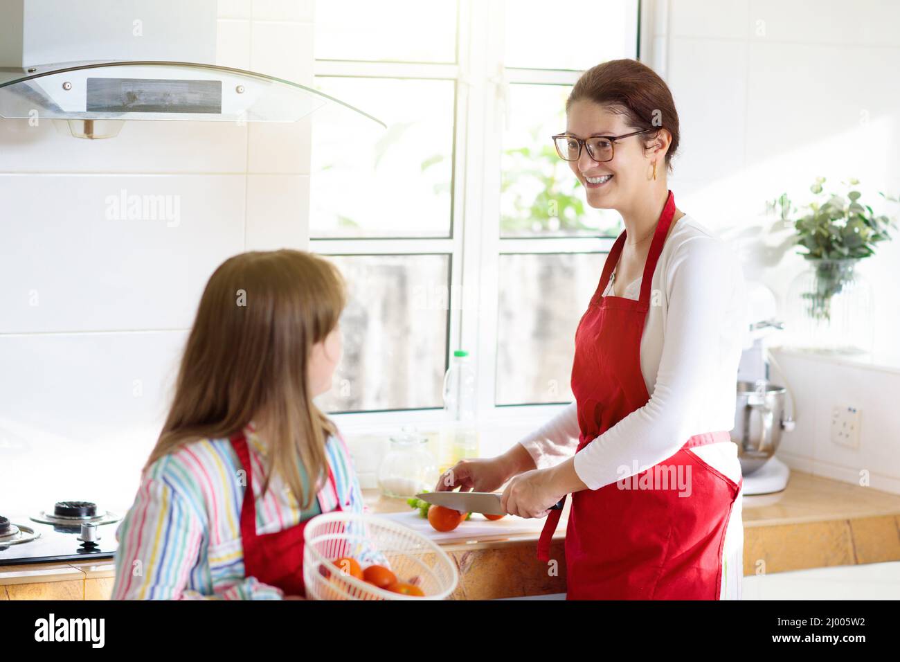 Mother and kid cook in white kitchen. Mom and child cooking at home ...