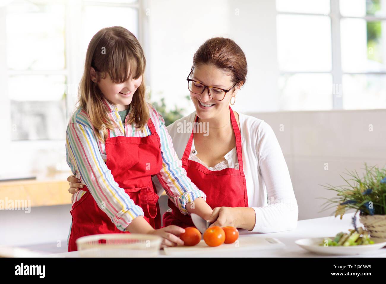Mother and kid cook in white kitchen. Mom and child cooking at home ...
