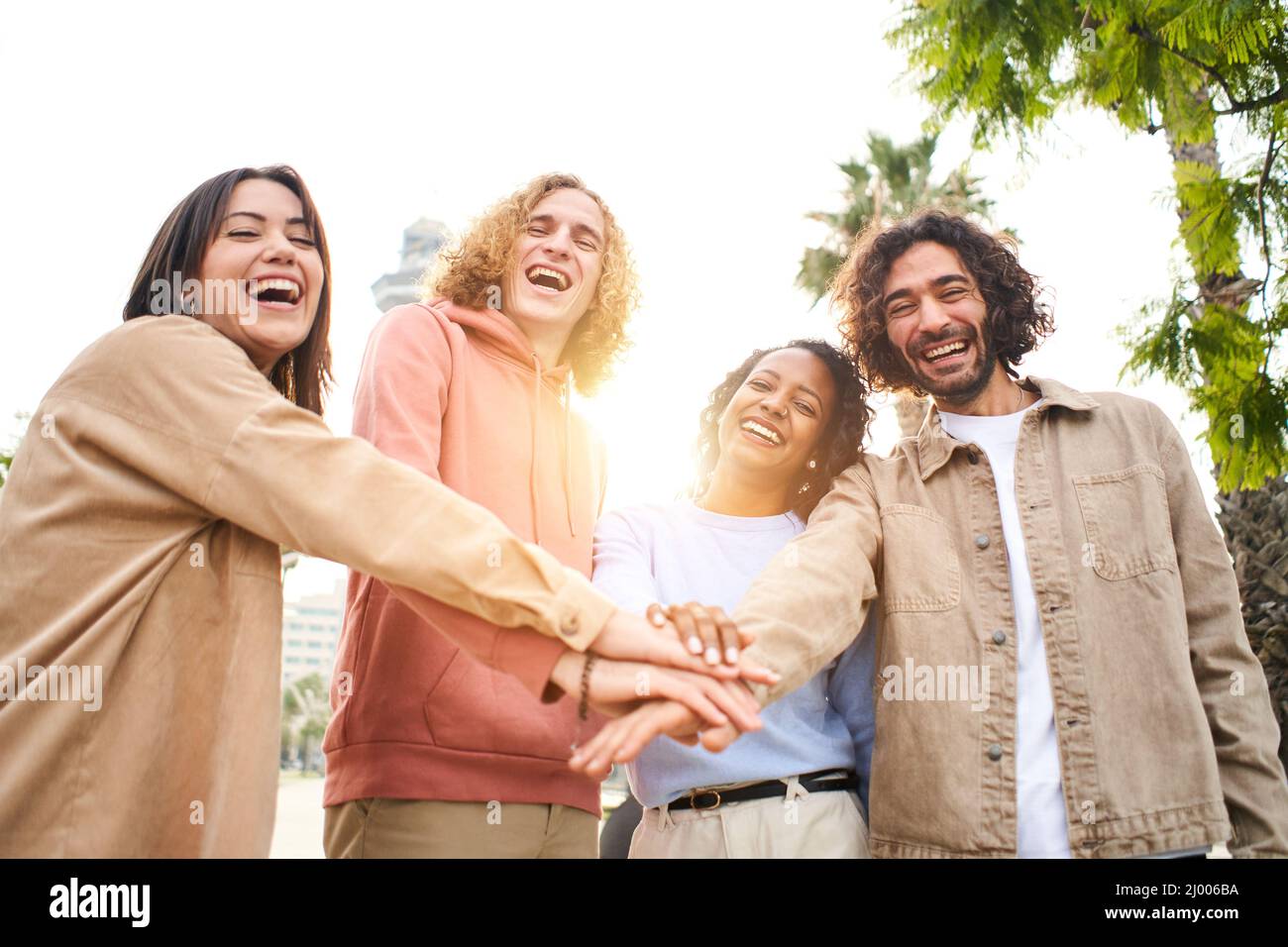 Group of young entrepreneur team stacking hands outdoors and looking at ...