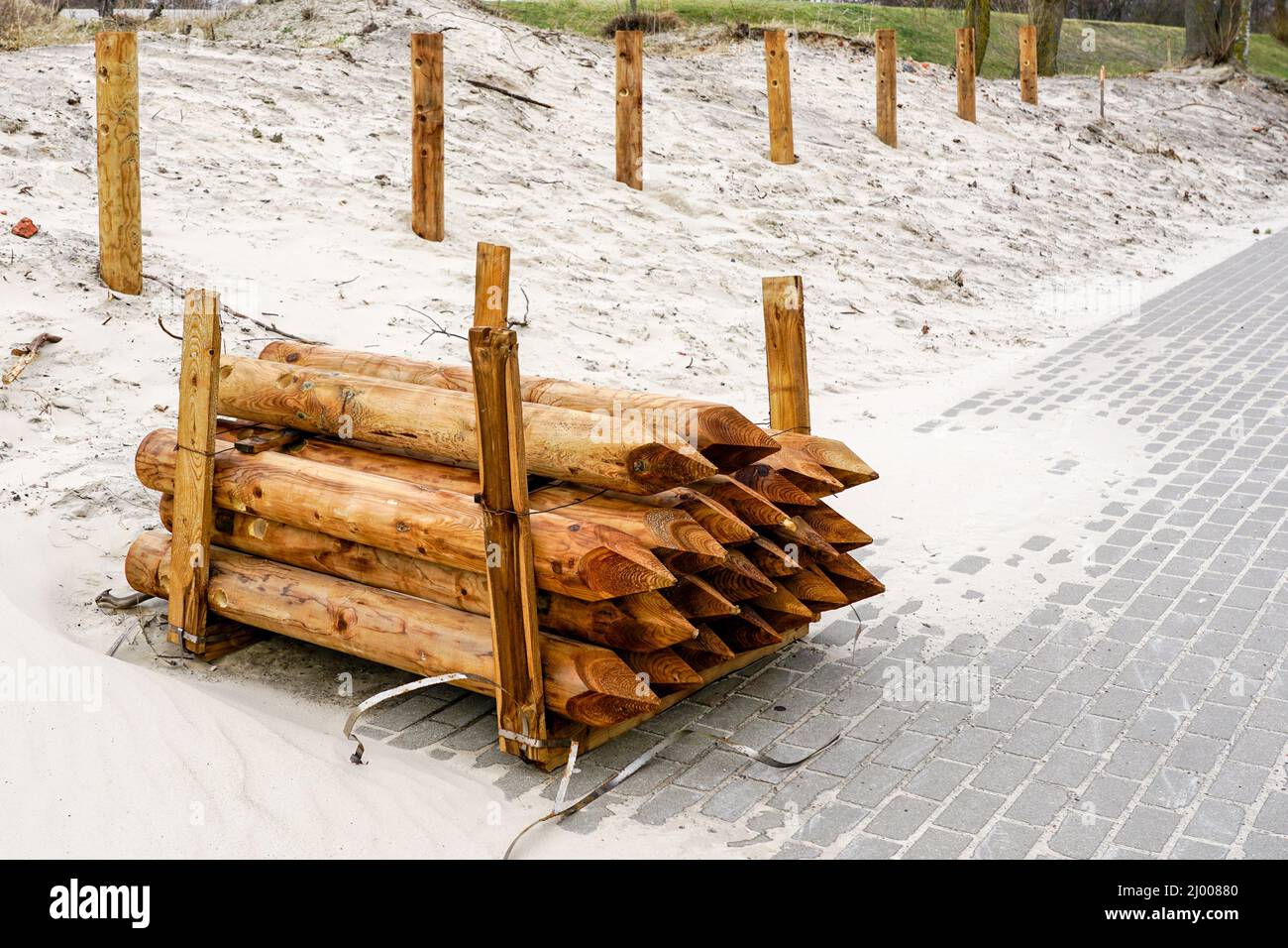 stack of thick round natural wooden fence posts with a sharpened end to ...