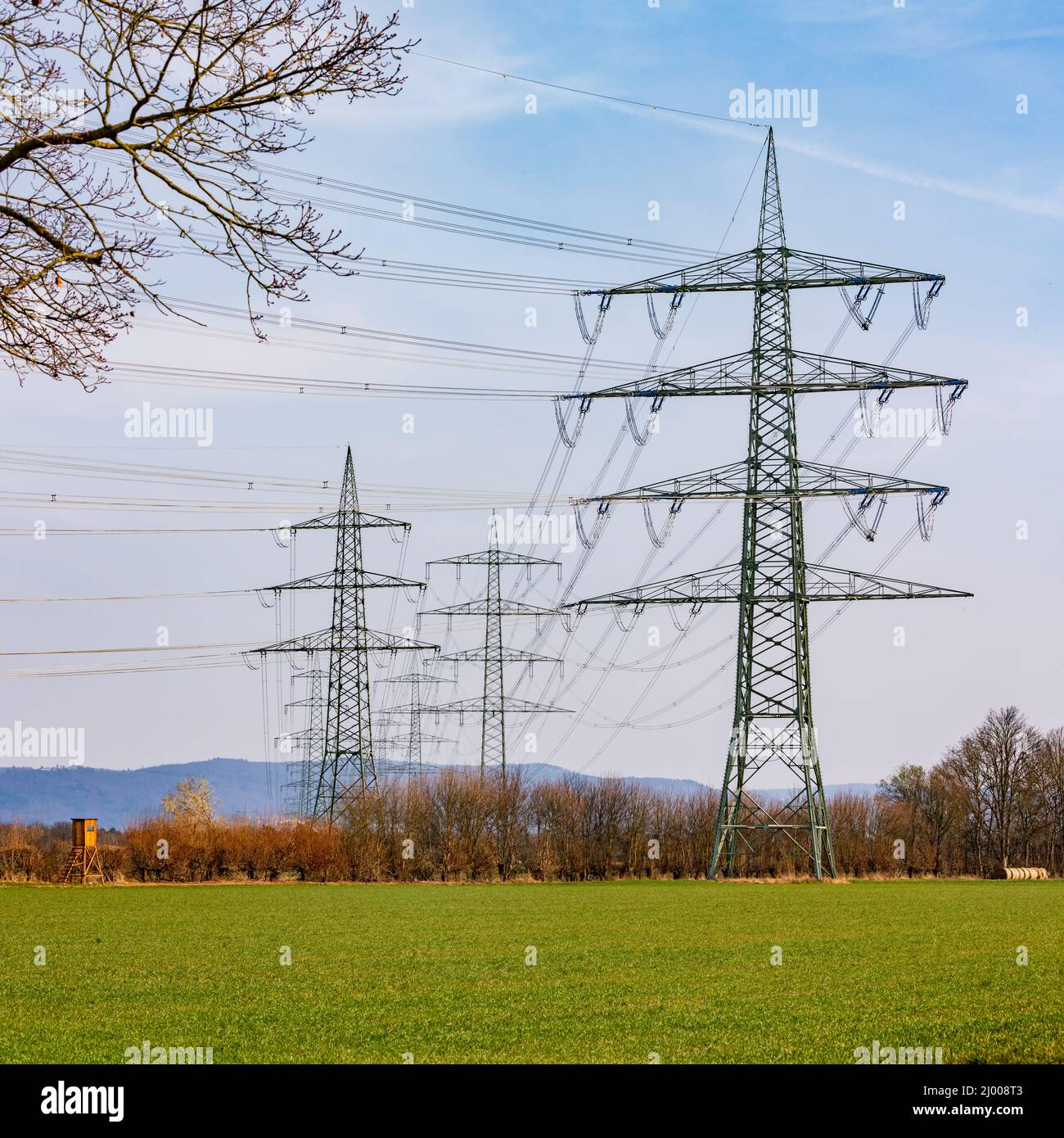 Panorama of high voltage pylons of different sizes in the field with a ...
