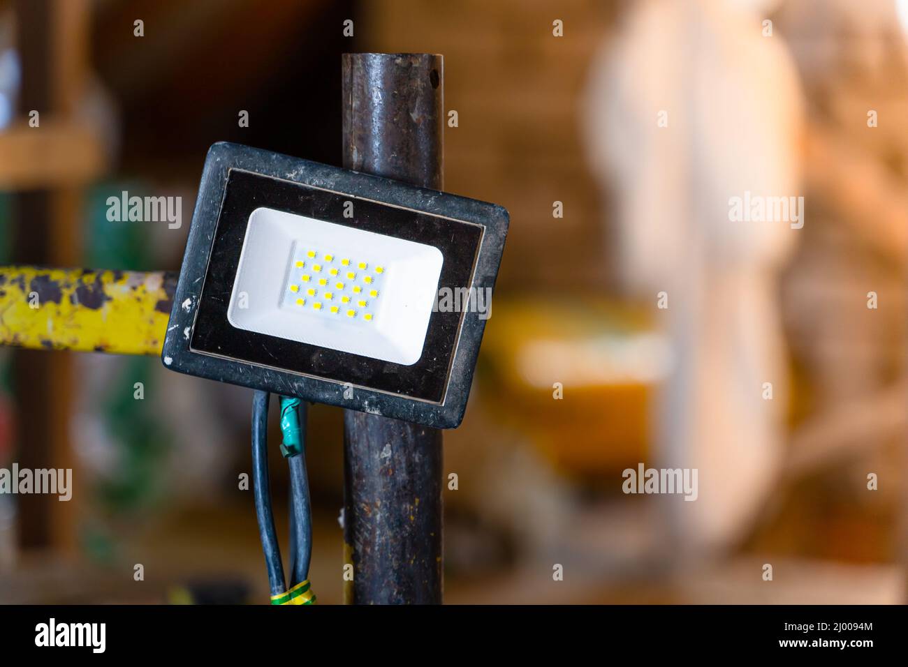 A compact LED spotlight with wires insulated with electrical tape hangs ...