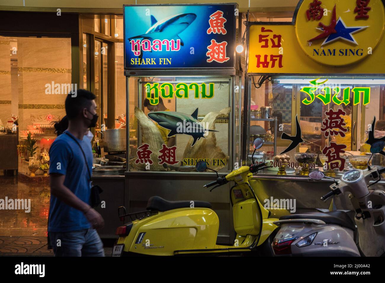 Bangkok, Thailand. 15th Mar, 2022. A man walks past the shark fin ...