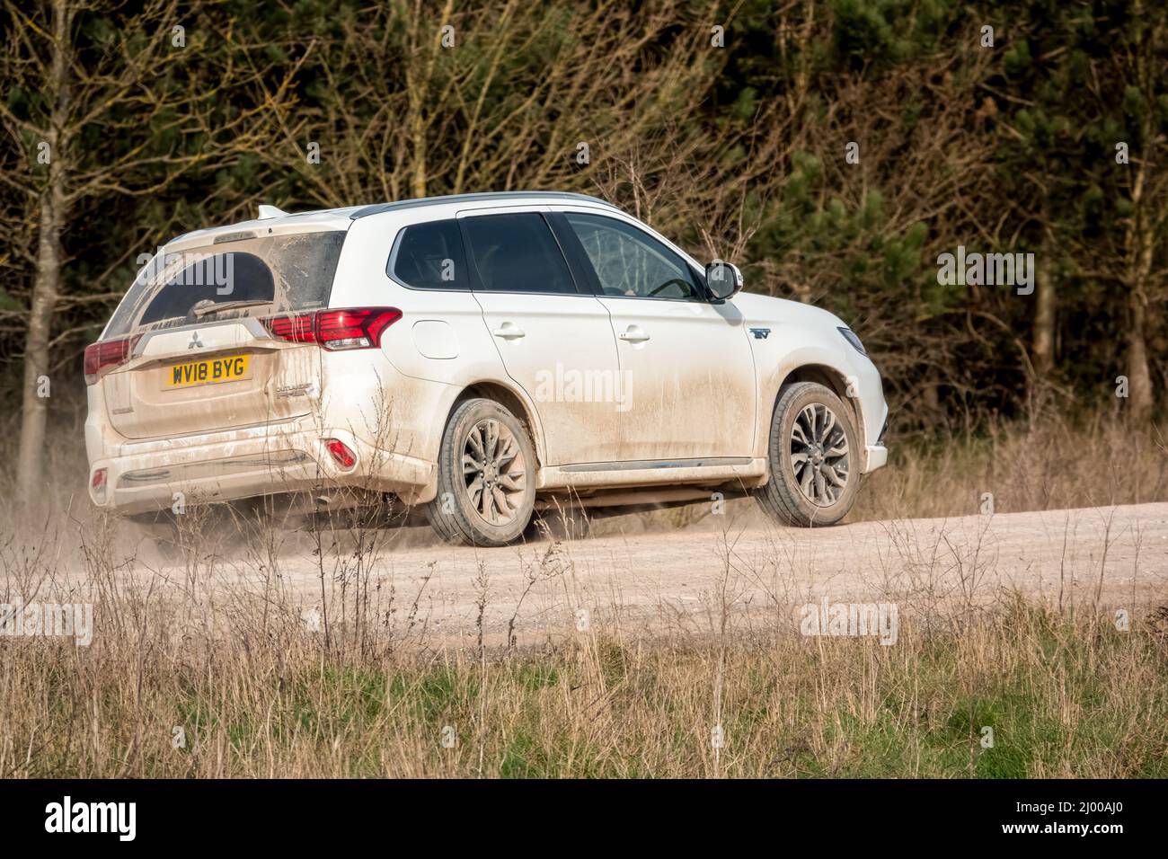 White Mitsubishi Outlander PHEV sport utility vehicle driving along an ...