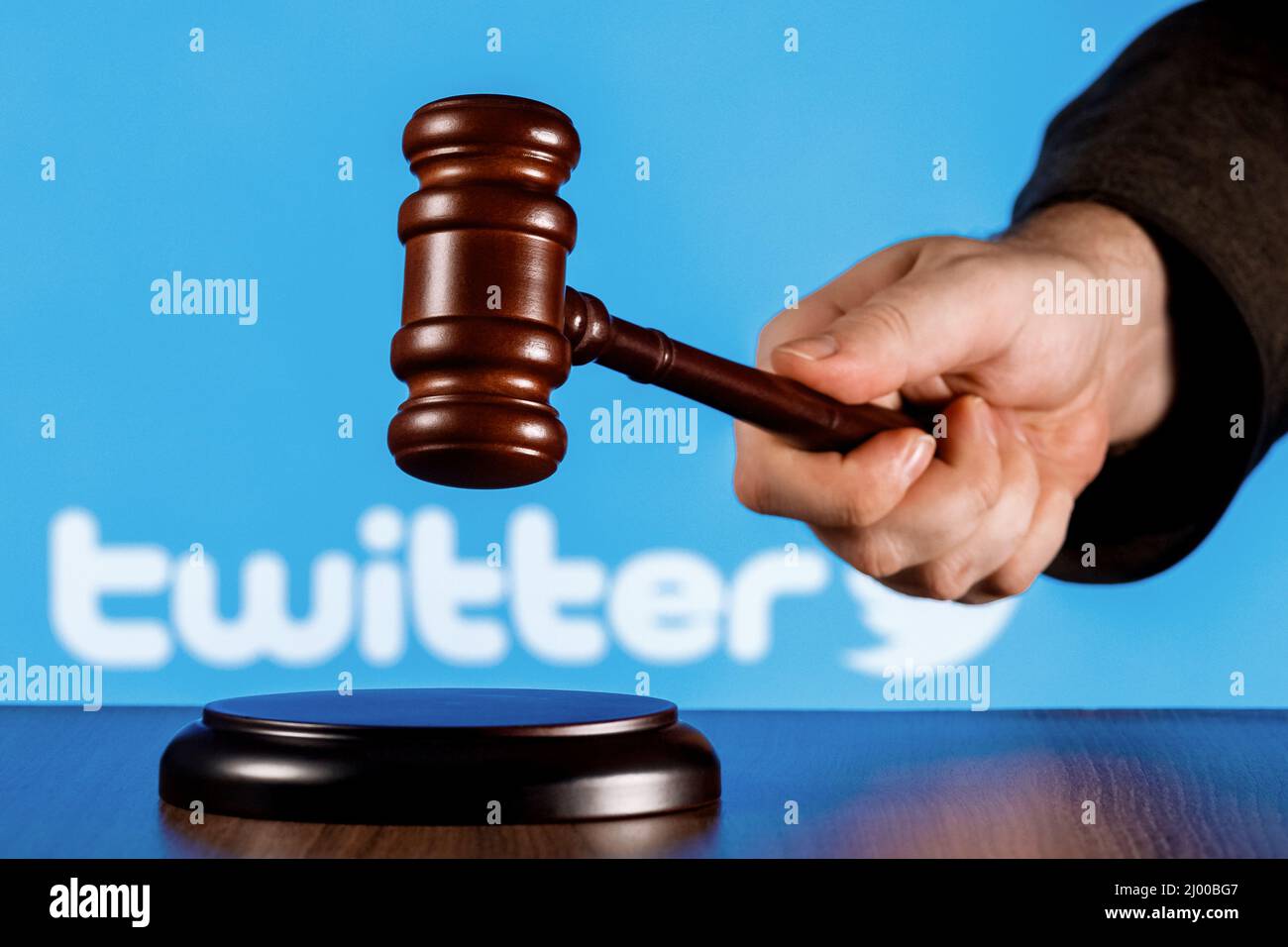 Gavel in judge hand against background of Twitter social network logo. The concept of trial ...