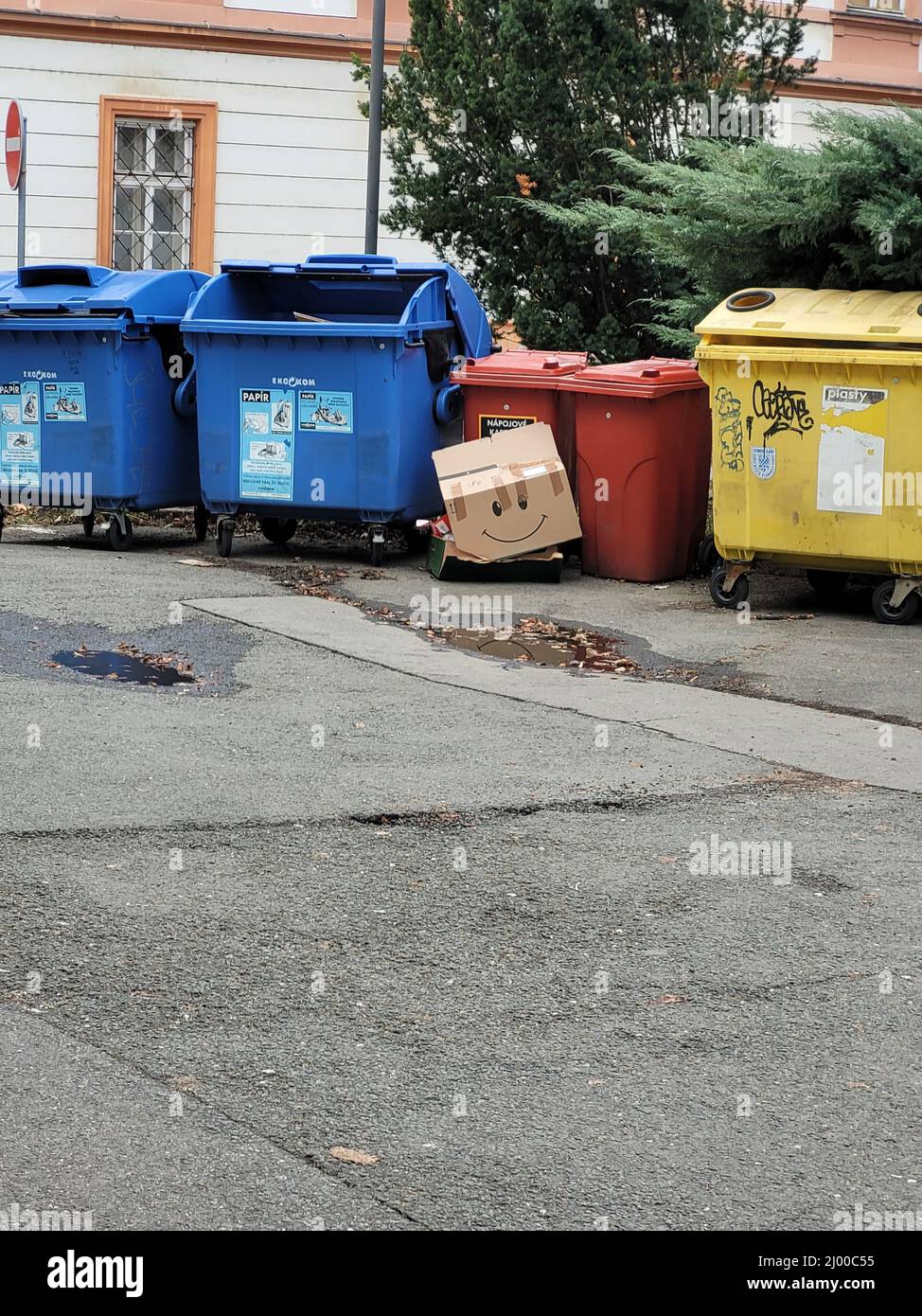 Vertical shot of trash cans on the street with a box with a smiley face ...