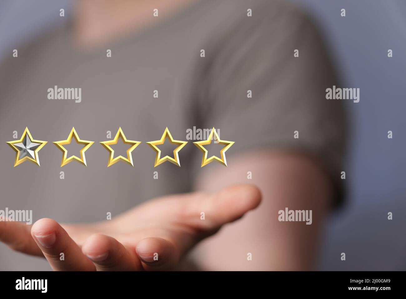 A close-up of a hand holding evaluation stars icon - feedback concept ...
