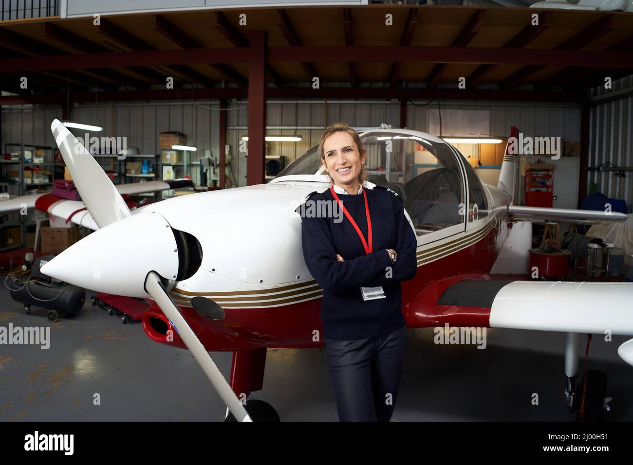 Young female pilot posing smiling in front of her plane inside the ...