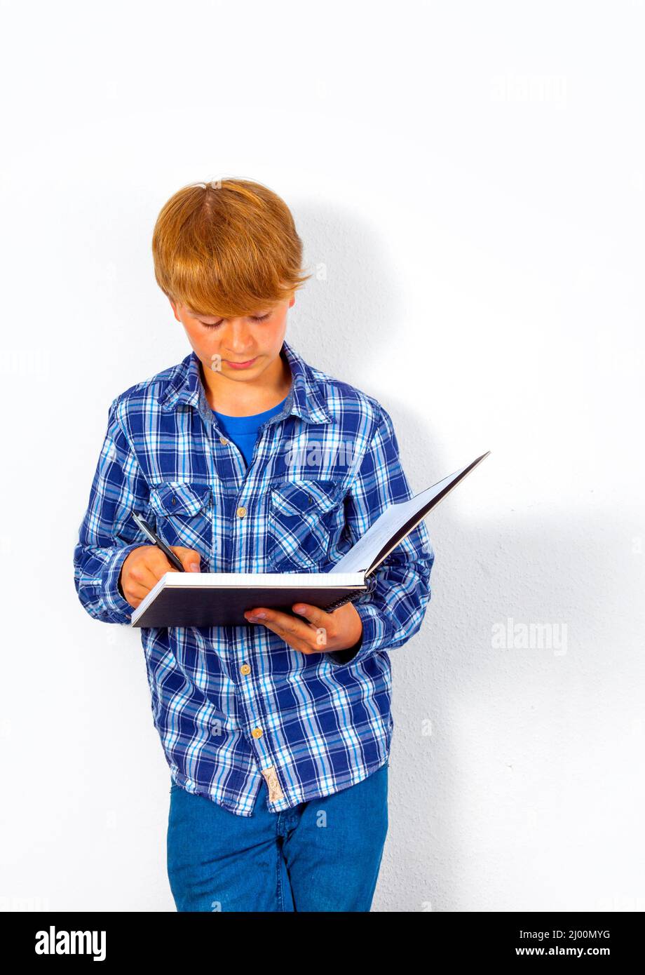 happy smart boy is writing into a book Stock Photo - Alamy